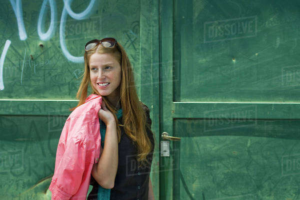 Fashionable young woman standing in front of graffitied door, jacket ...