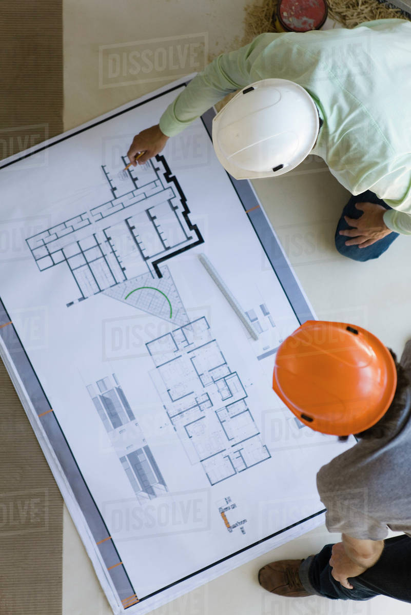 Two men crouching looking over blueprints spread out on floor - Stock ...