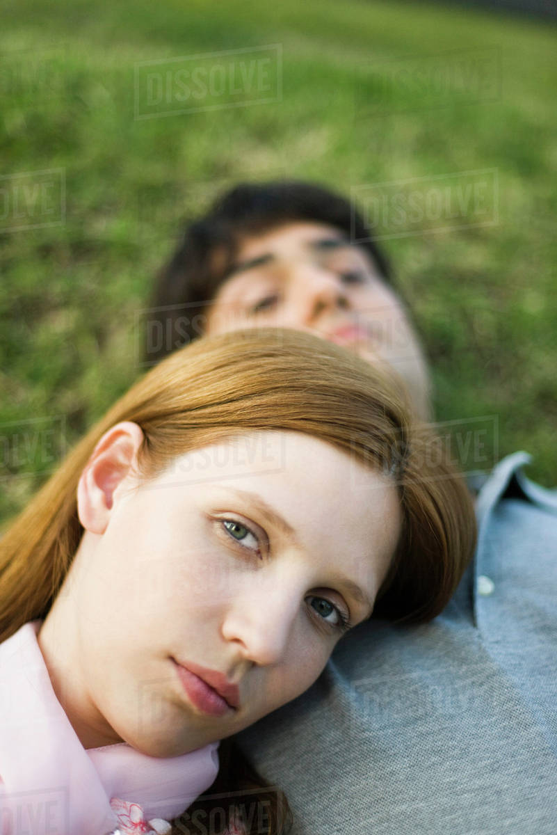 Young couple lying on ground, woman resting head on man's chest ...
