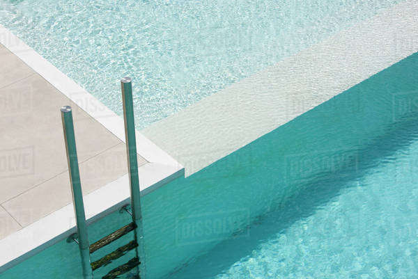 Swimming pool ladder at deep end separated from shallow pool by ledge ...