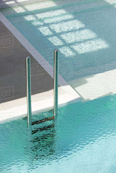 Swimming pool ladder at deep end separated from shallow pool by ledge ...