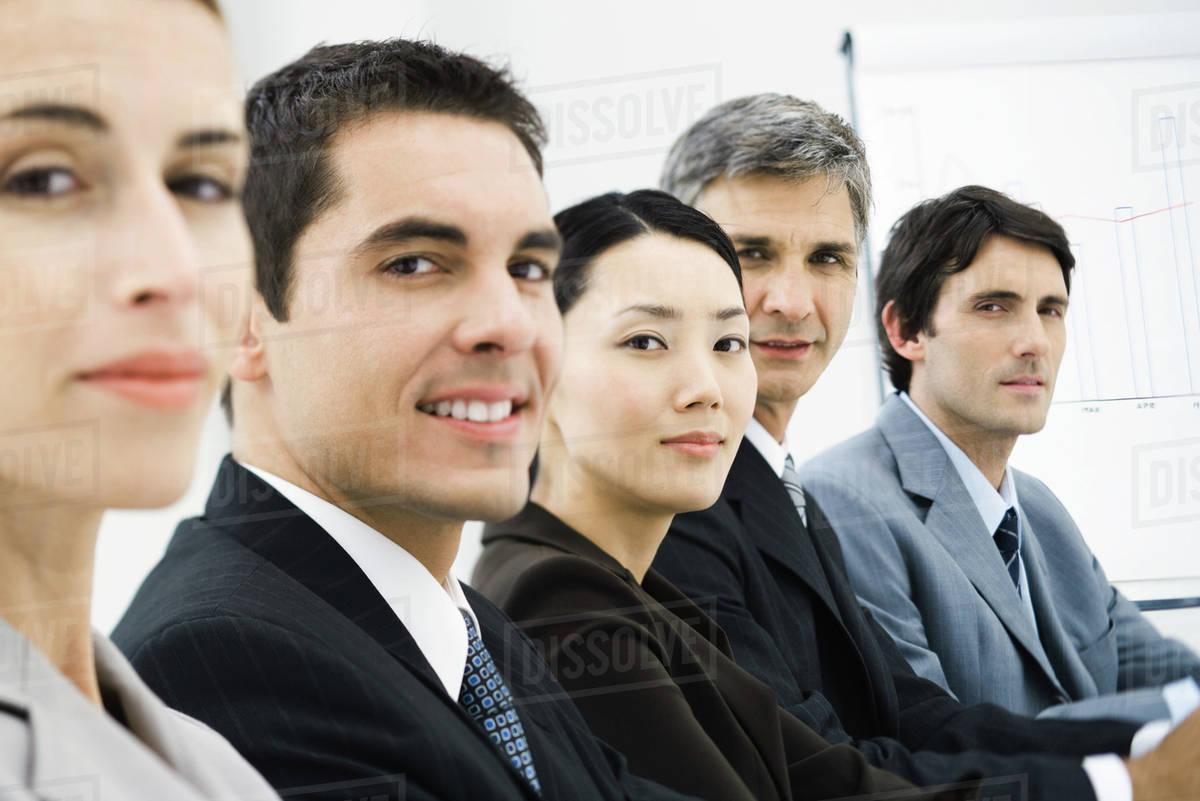 Row of business executives in conference room, smiling at camera ...