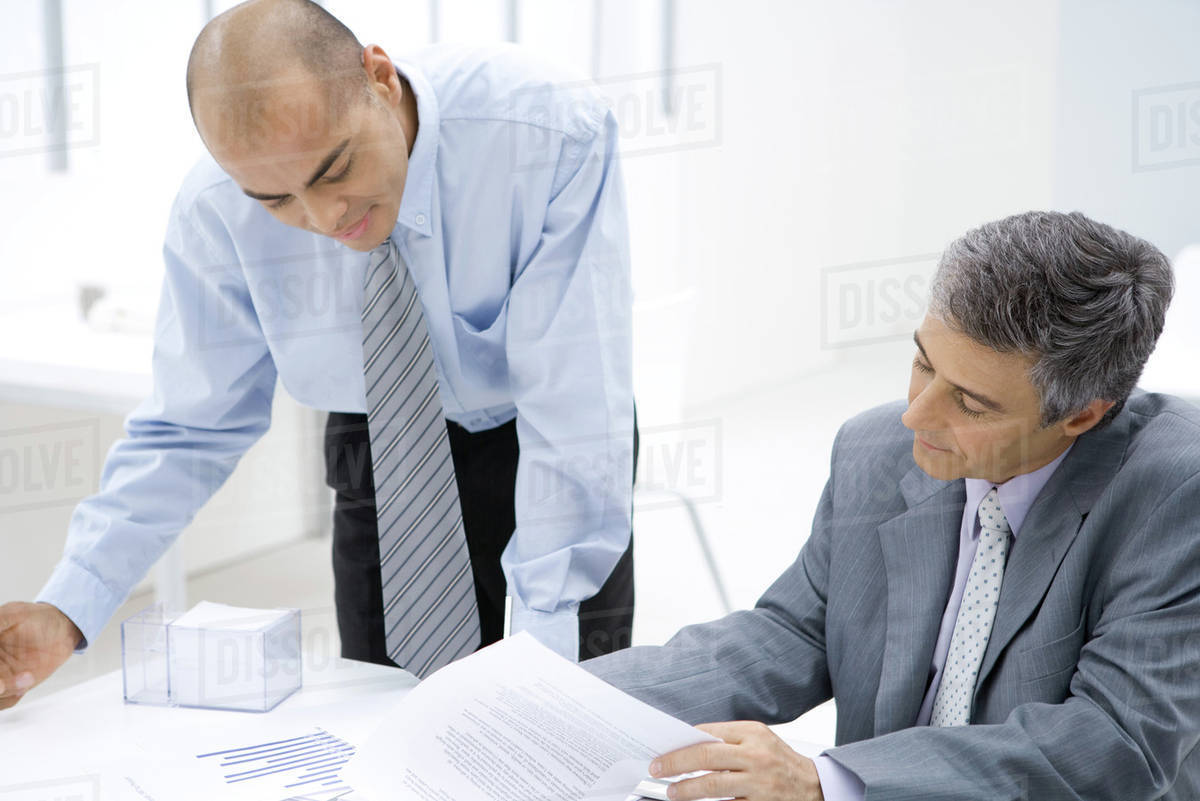 Two businessmen looking over documents together - Stock Photo - Dissolve
