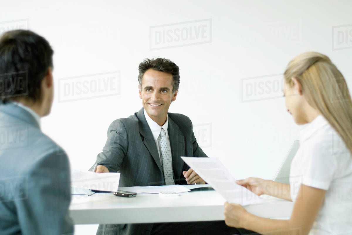 Businessman discussing contract with couple, smiling - Royalty-free ...