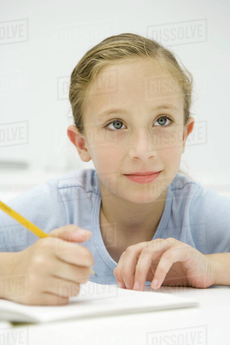 Girl sitting at table, writing in notebook, looking away - Royalty-free ...