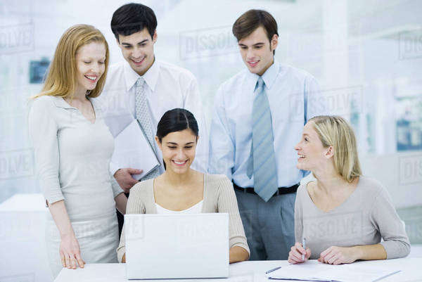 Group of professionals gathered around laptop computer, smiling ...