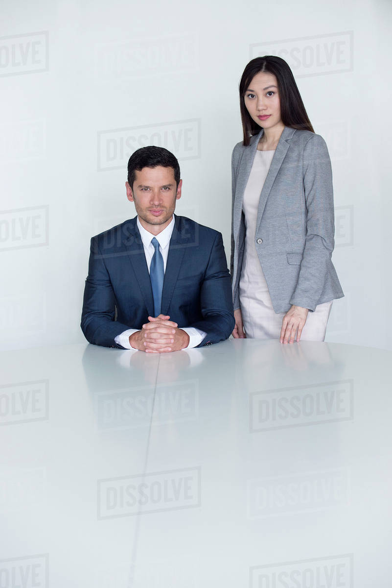 Executive seated beside standing assistant, portrait - Stock Photo ...