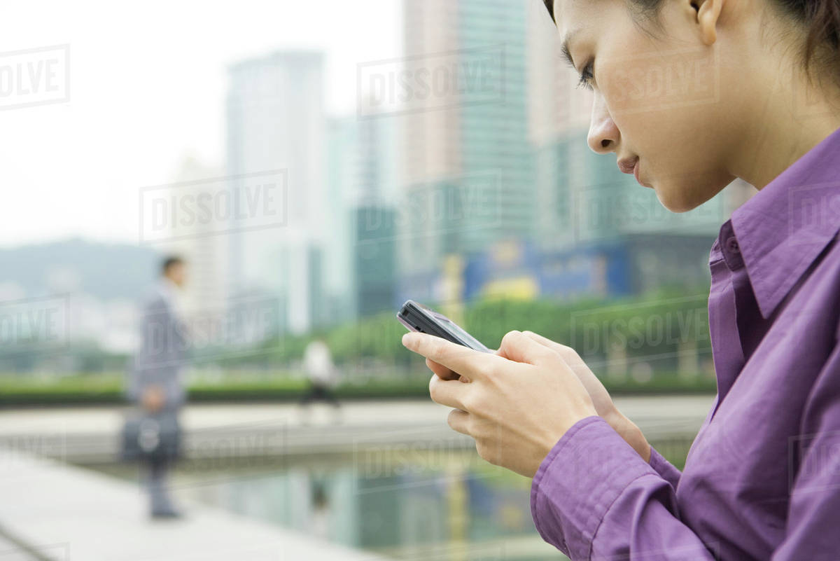 Businesswoman looking at cell phone - Royalty-free Stock Photo | Dissolve