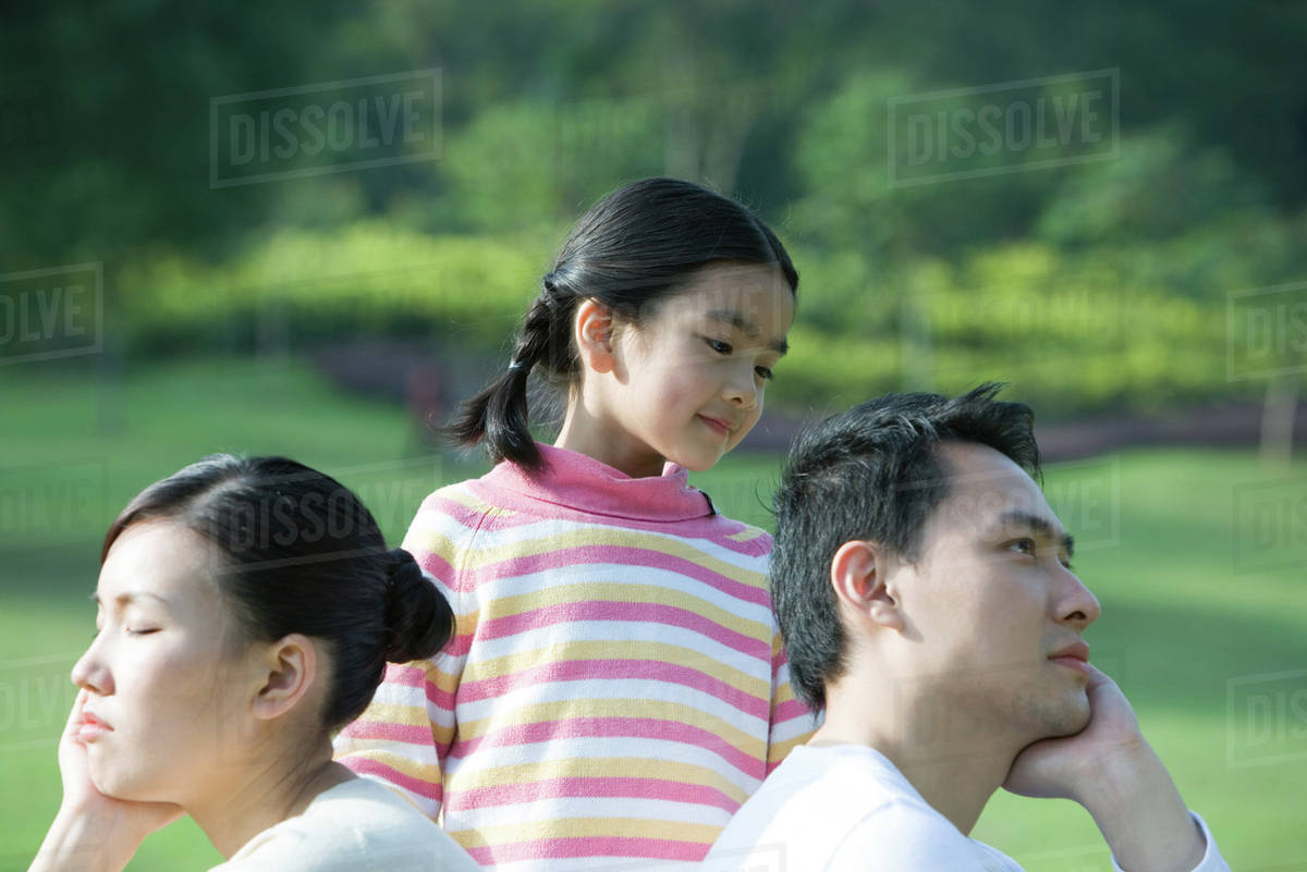 Girl looking at parents sitting back to back - Royalty-free Stock Photo ...