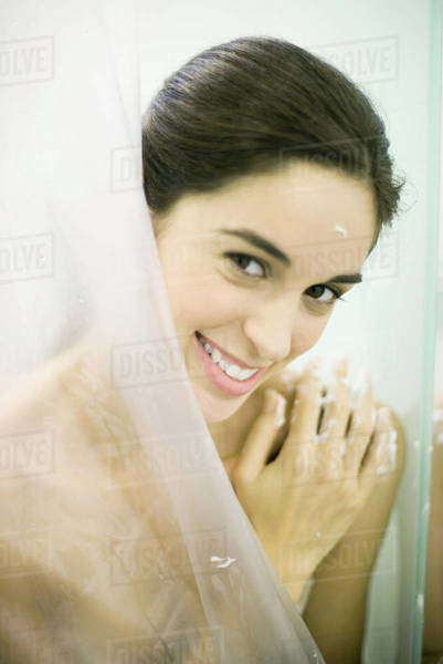 Young woman standing behind shower curtain, smiling at camera - Royalty ...