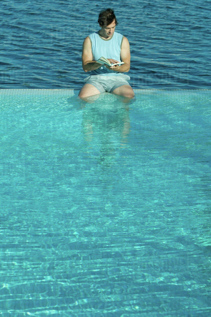 Man sitting in infinity pool, reading - Royalty-free Stock Photo | Dissolve