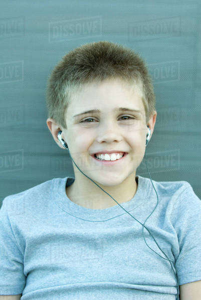 Boy listening to earphones, smiling at camera, portrait - Royalty-free ...