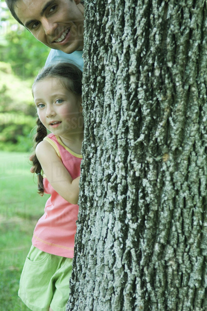 Girl and father peeking around tree trunk - Royalty-free Stock Photo ...