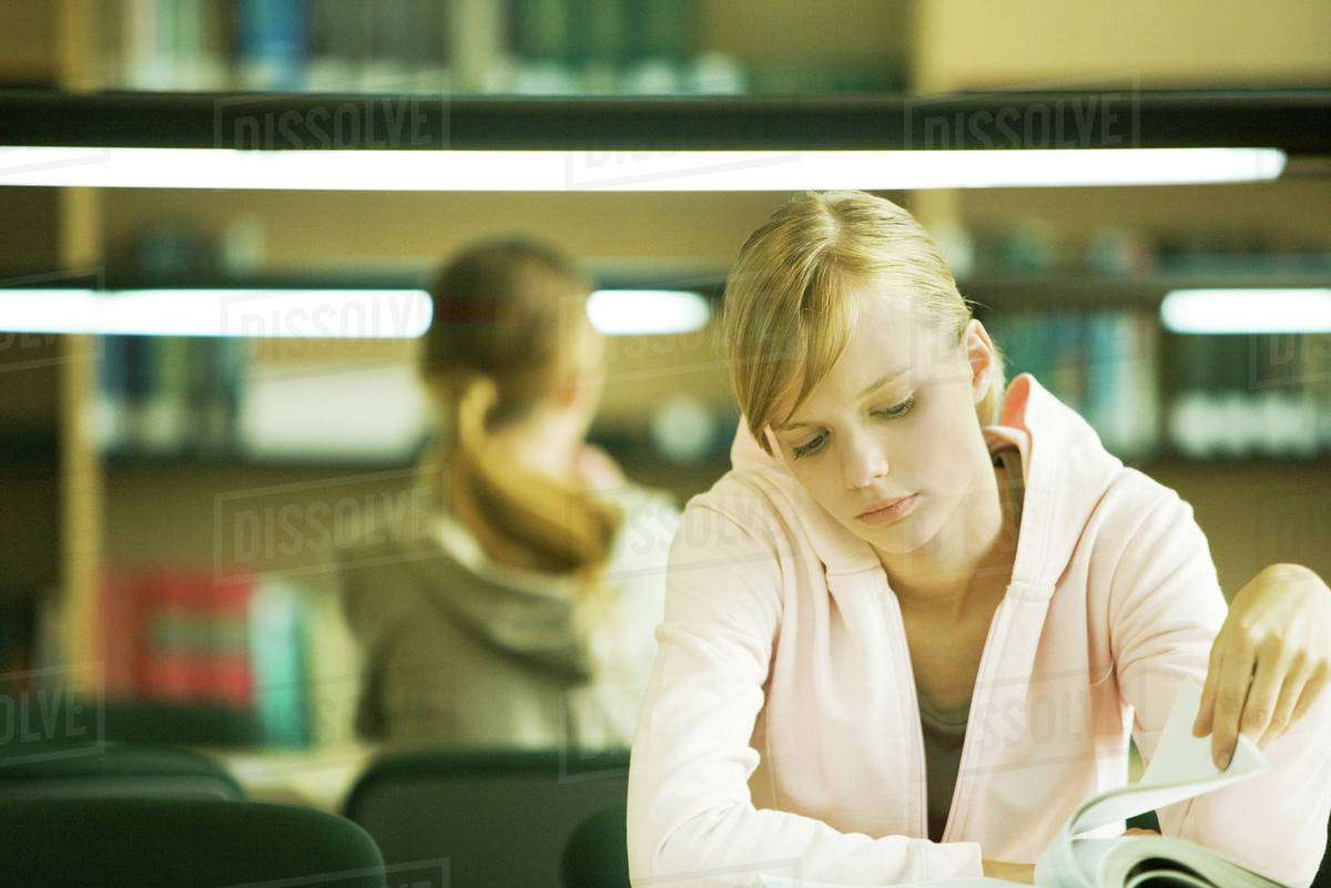 Female college student sitting at table in library, studying - Royalty ...