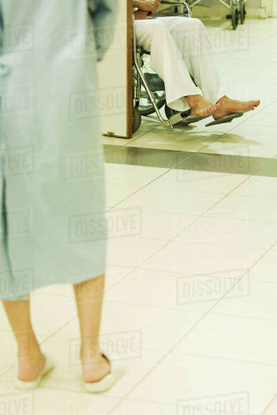 Patients in hospital, one standing, one sitting in wheelchair, cropped ...