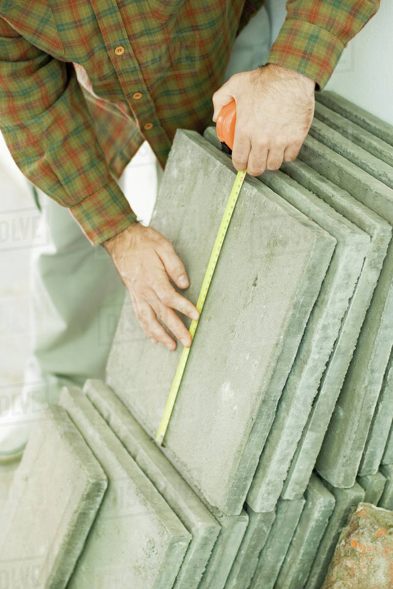 Man measuring paving stone with measuring tape, cropped view - Stock ...