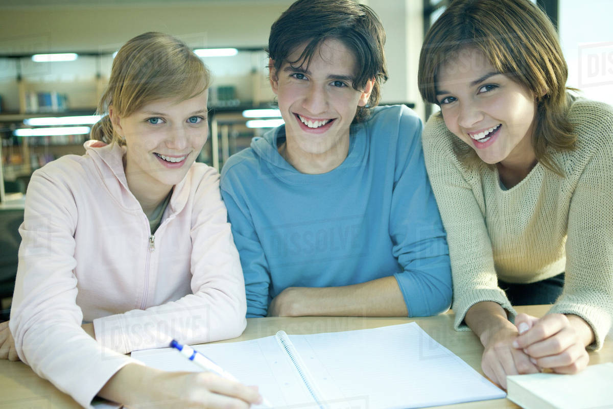 Three students studying together, smiling at camera - Royalty-free ...