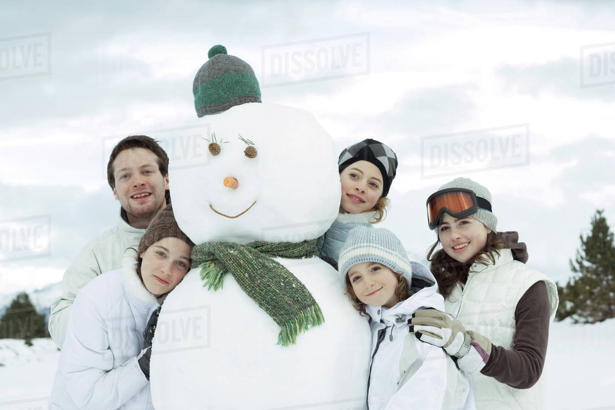 Group of young friends gathered around snowman - Royalty-free Stock ...