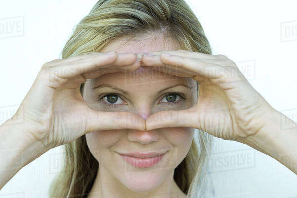 Woman looking at camera through finger frame, close-up - Royalty-free ...