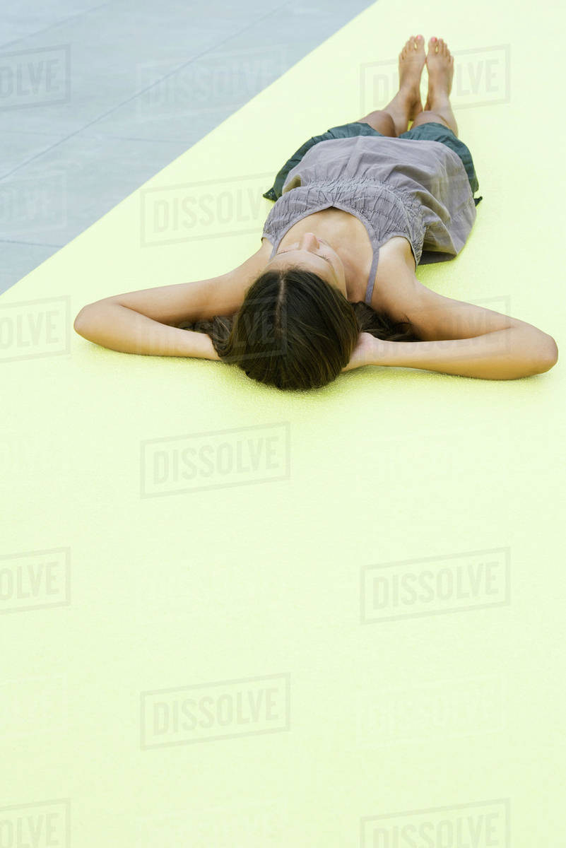 Teenage girl lying on the ground with hands behind head - Royalty-free ...