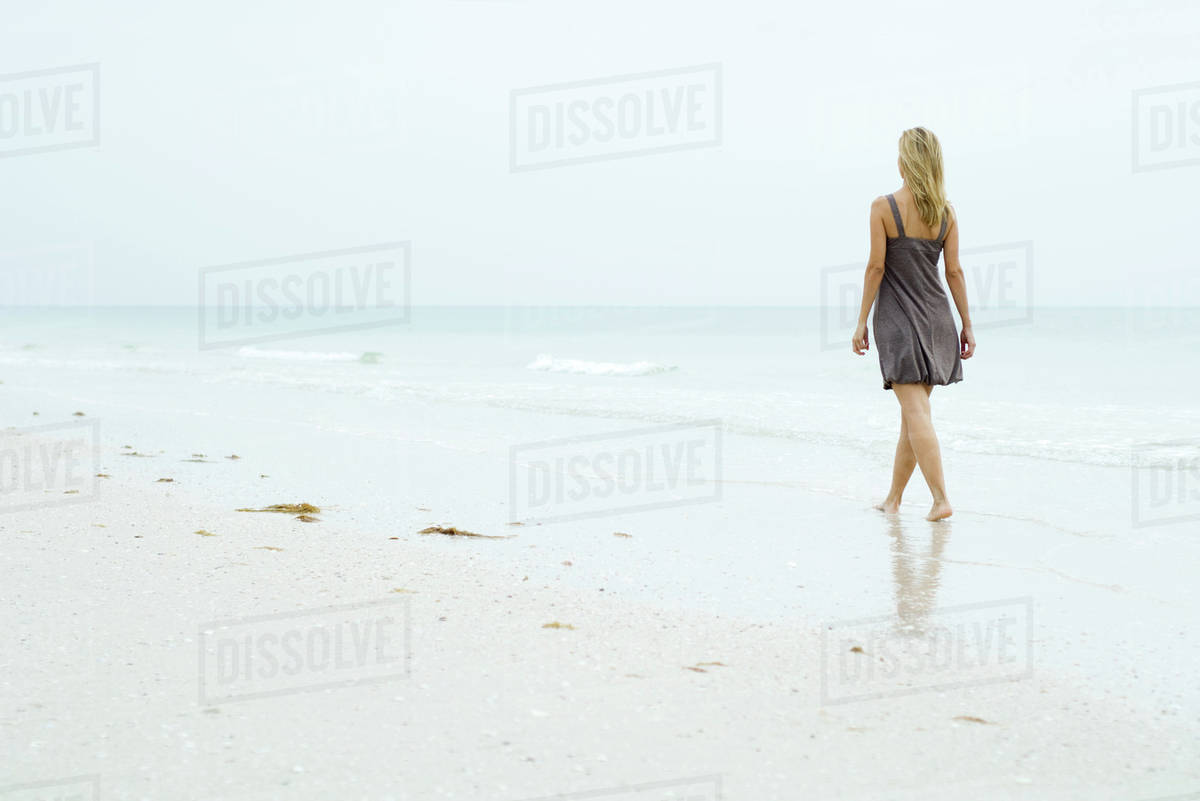 Woman in sundress walking along beach, rear view - Royalty-free Stock ...