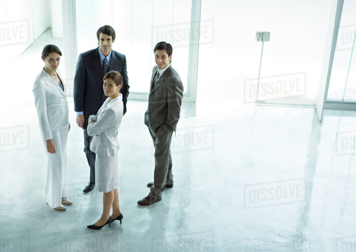 Four executives standing in office building lobby - Stock Photo - Dissolve