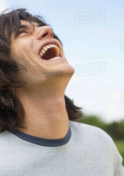 Young man throwing head back and laughing - Stock Photo - Dissolve
