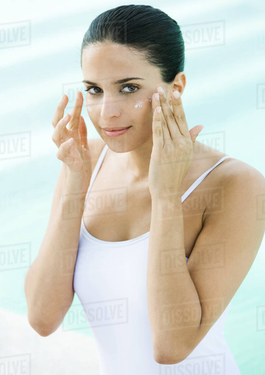 Woman applying sunscreen to face - Stock Photo - Dissolve