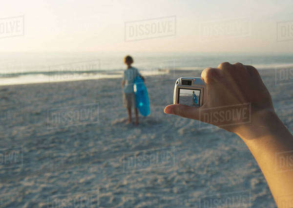 Taking photo of child with digital camera on beach, focus on hand ...
