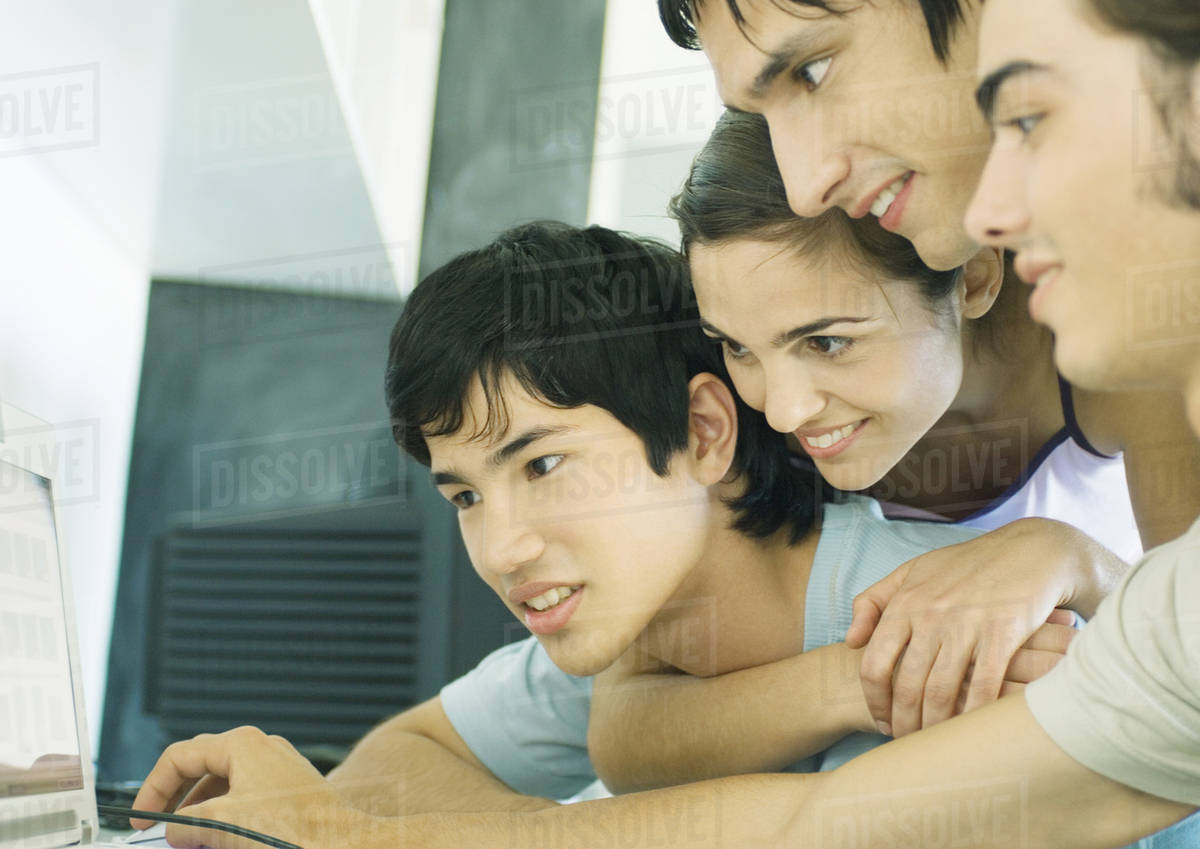 Four young adult friends looking at computer screen together - Stock ...