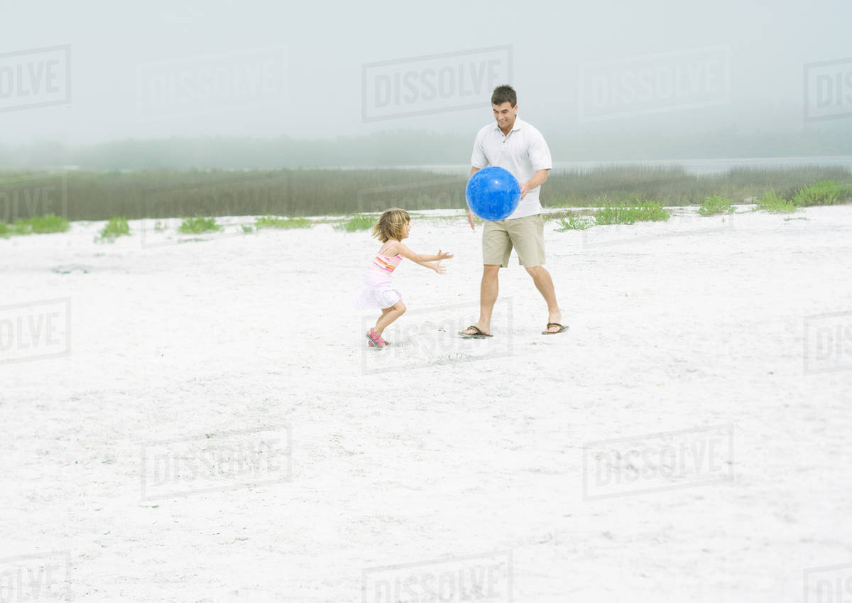 Man playing ball with daughter on sand - Royalty-free Stock Photo ...