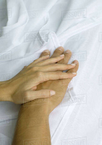 Woman's hand on top of man's, on sheets - Royalty-free Stock Photo ...
