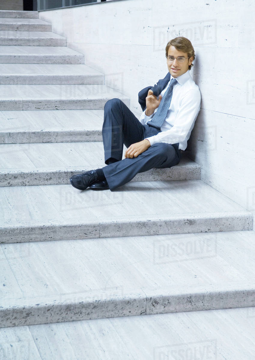 Businessman sitting on steps, smiling - Royalty-free Stock Photo | Dissolve