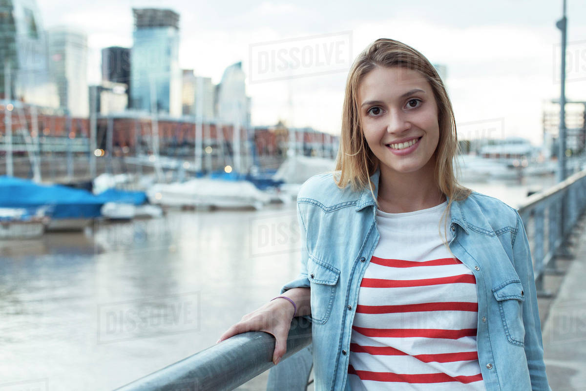 Young woman leaning against railing, smiling, portrait - Royalty-free ...