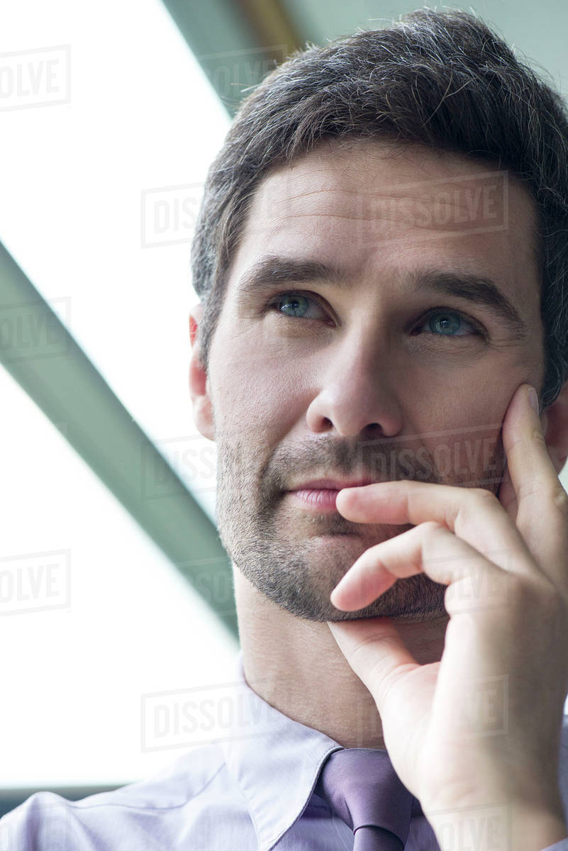 Businessman looking up in thought, portrait - Stock Photo - Dissolve