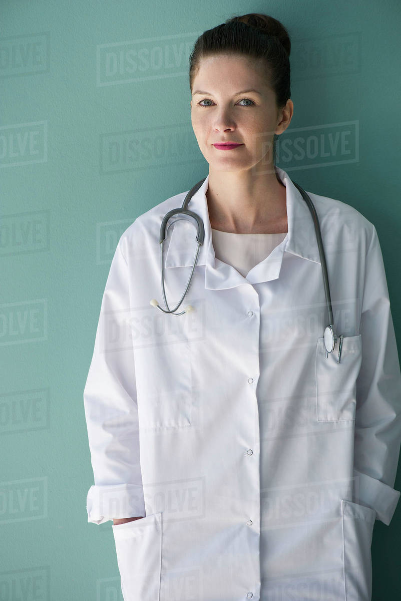 Doctor leaning against wall, portrait - Royalty-free Stock Photo | Dissolve