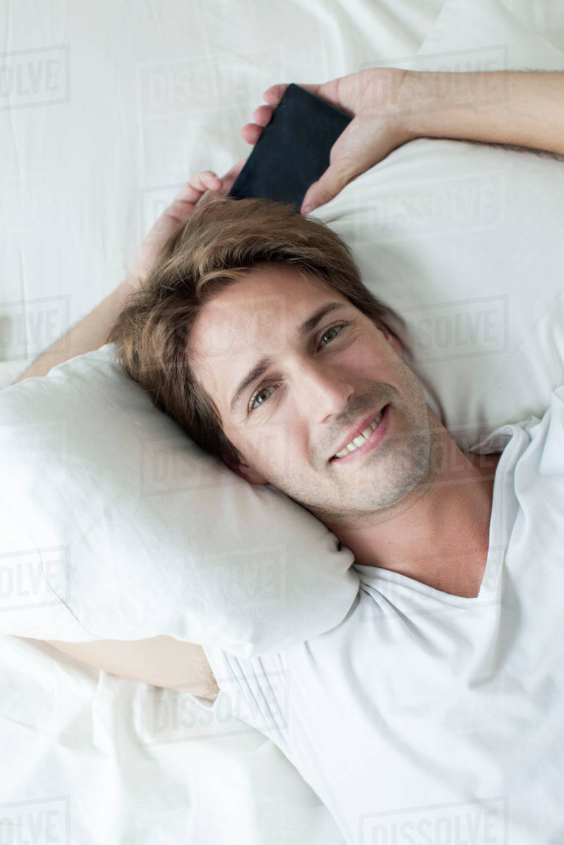 Man relaxing on bed, portrait - Stock Photo - Dissolve