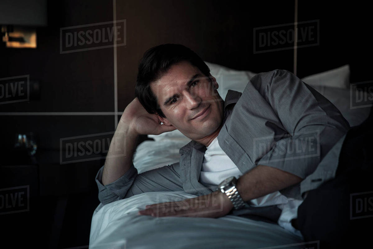 Man relaxing on bed, portrait - Royalty-free Stock Photo | Dissolve