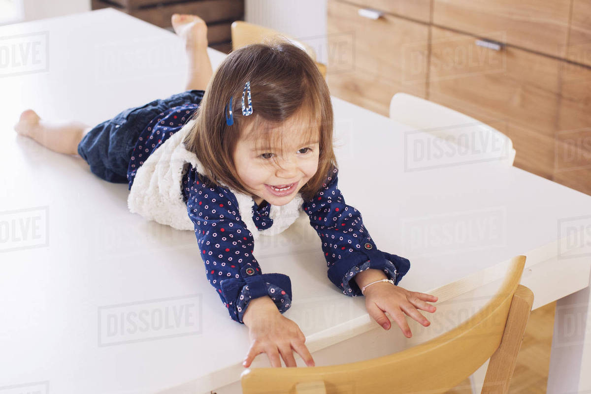 Little girl lying on top of table - Royalty-free Stock Photo | Dissolve