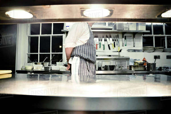 Chef standing in commercial kitchen - Royalty-free Stock Photo | Dissolve