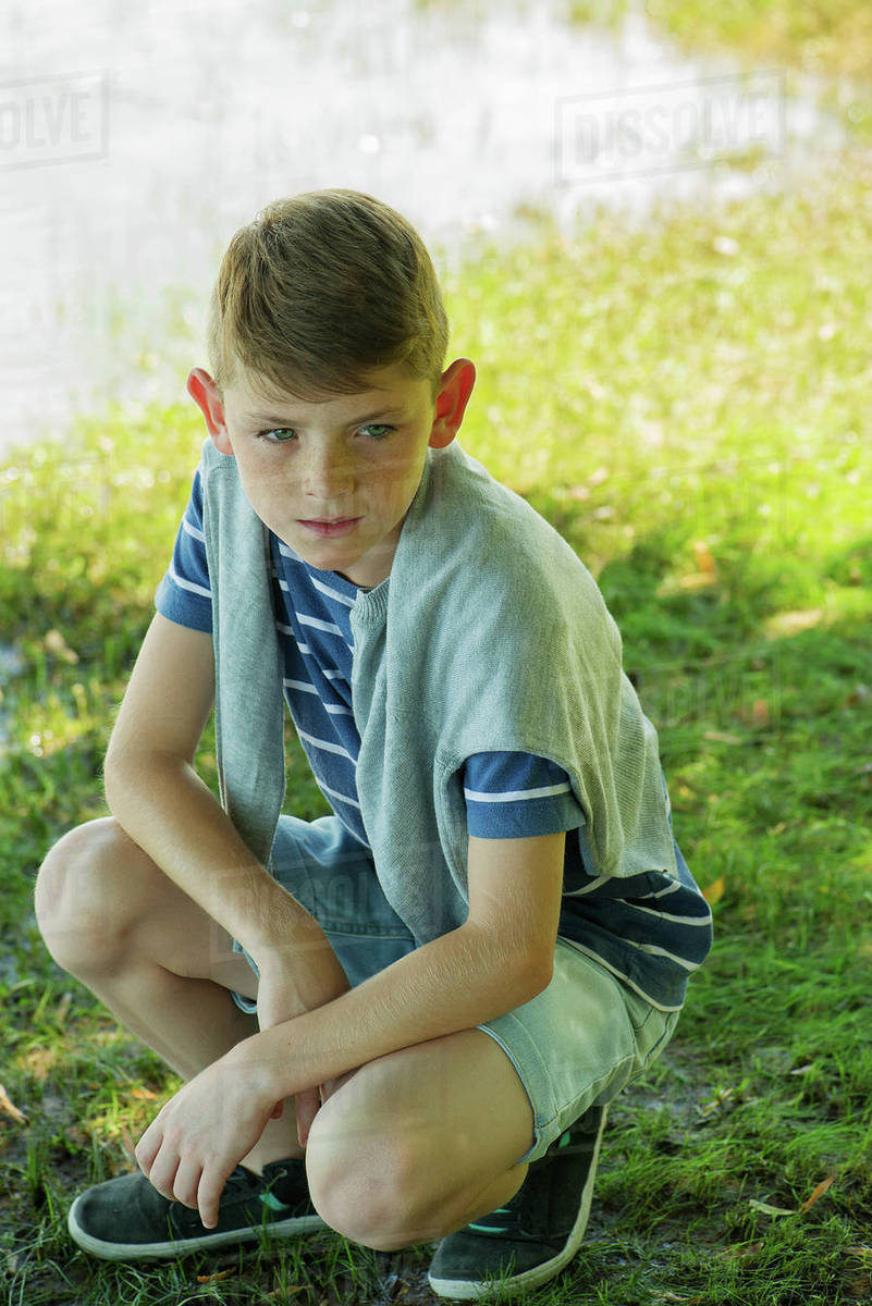 Boy crouching in nature - Royalty-free Stock Photo | Dissolve