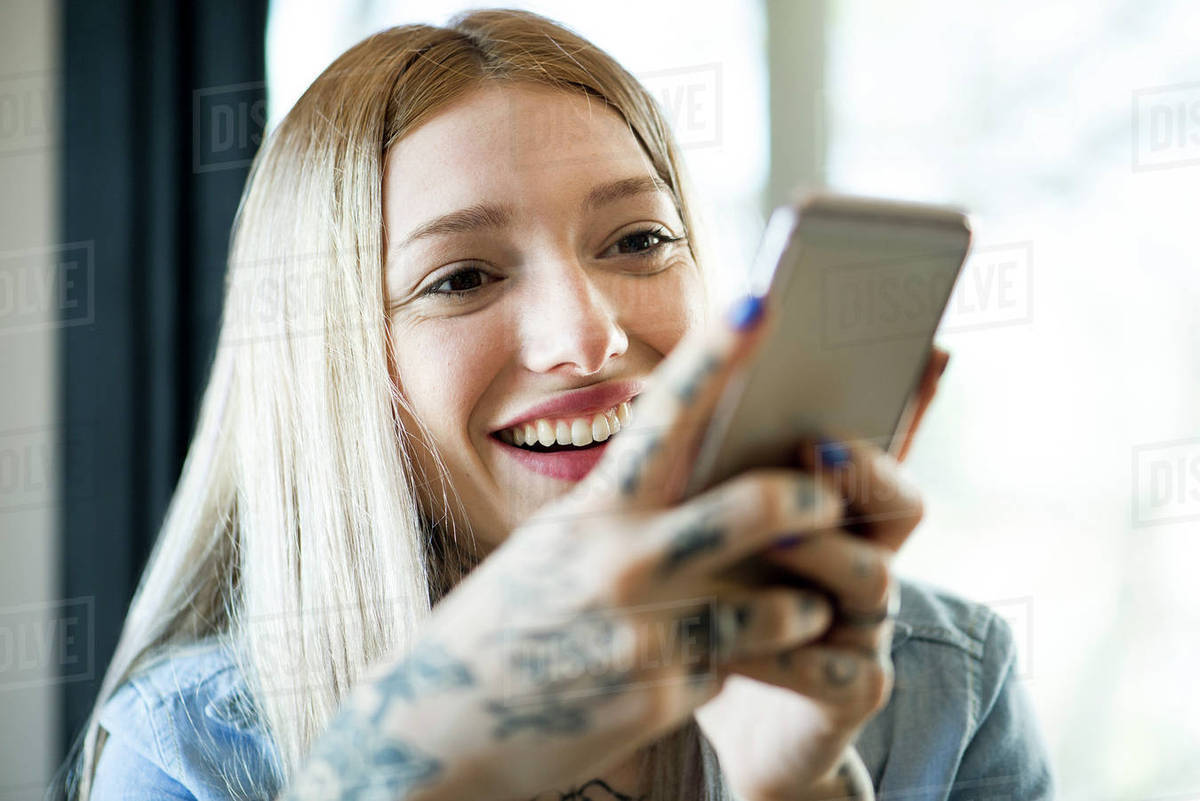 Woman using smartphone and smiling cheerfully - Royalty-free Stock ...