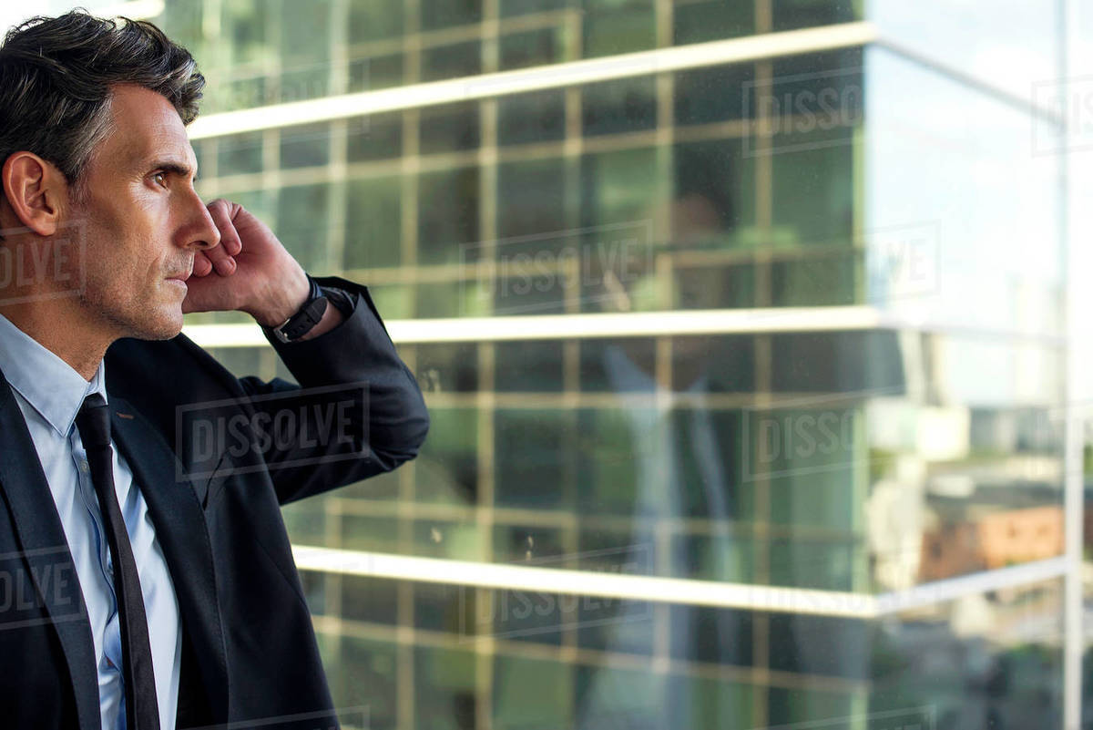 Man looking through window in high rise building - Stock Photo - Dissolve