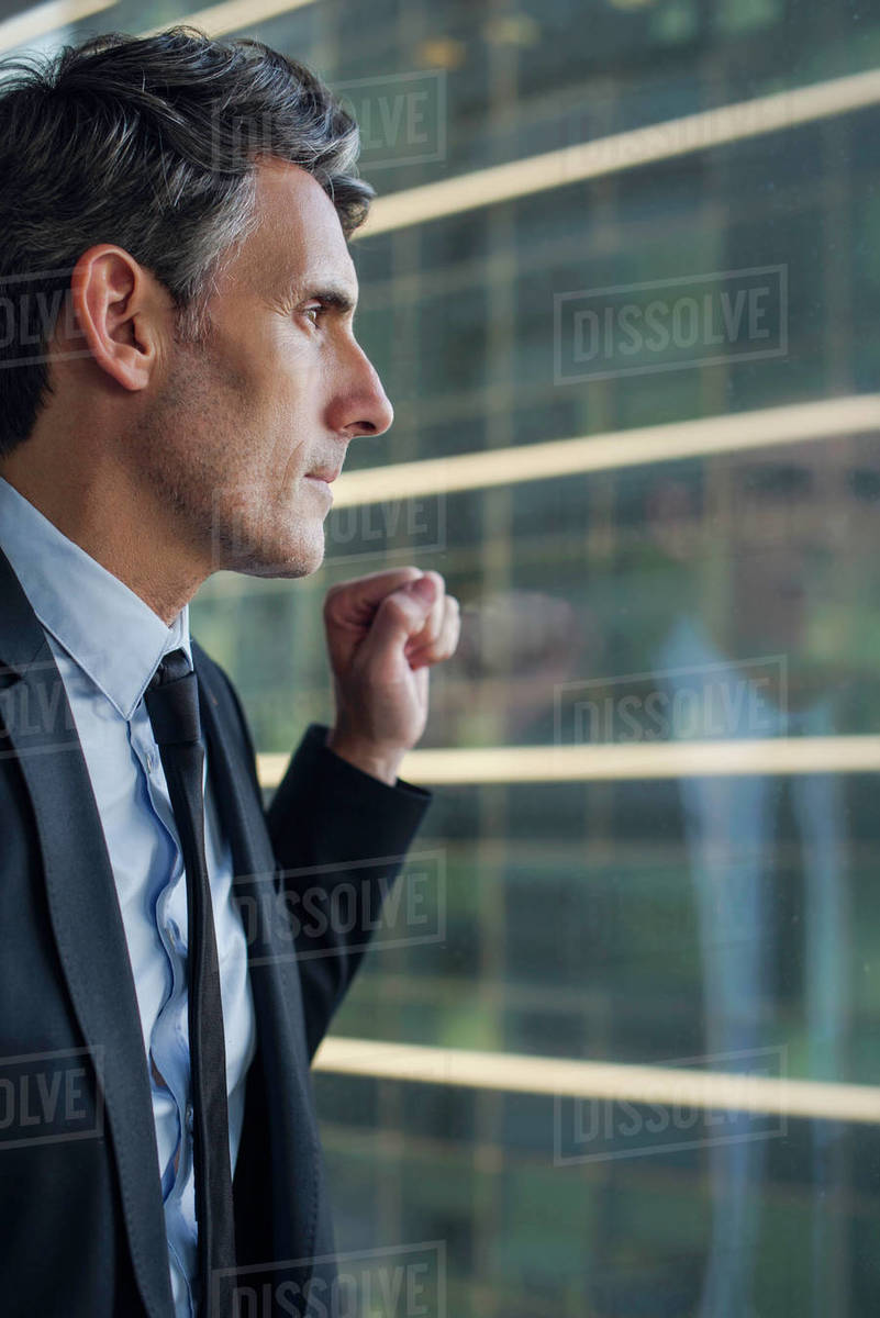 Man looking through window in high rise building - Stock Photo - Dissolve