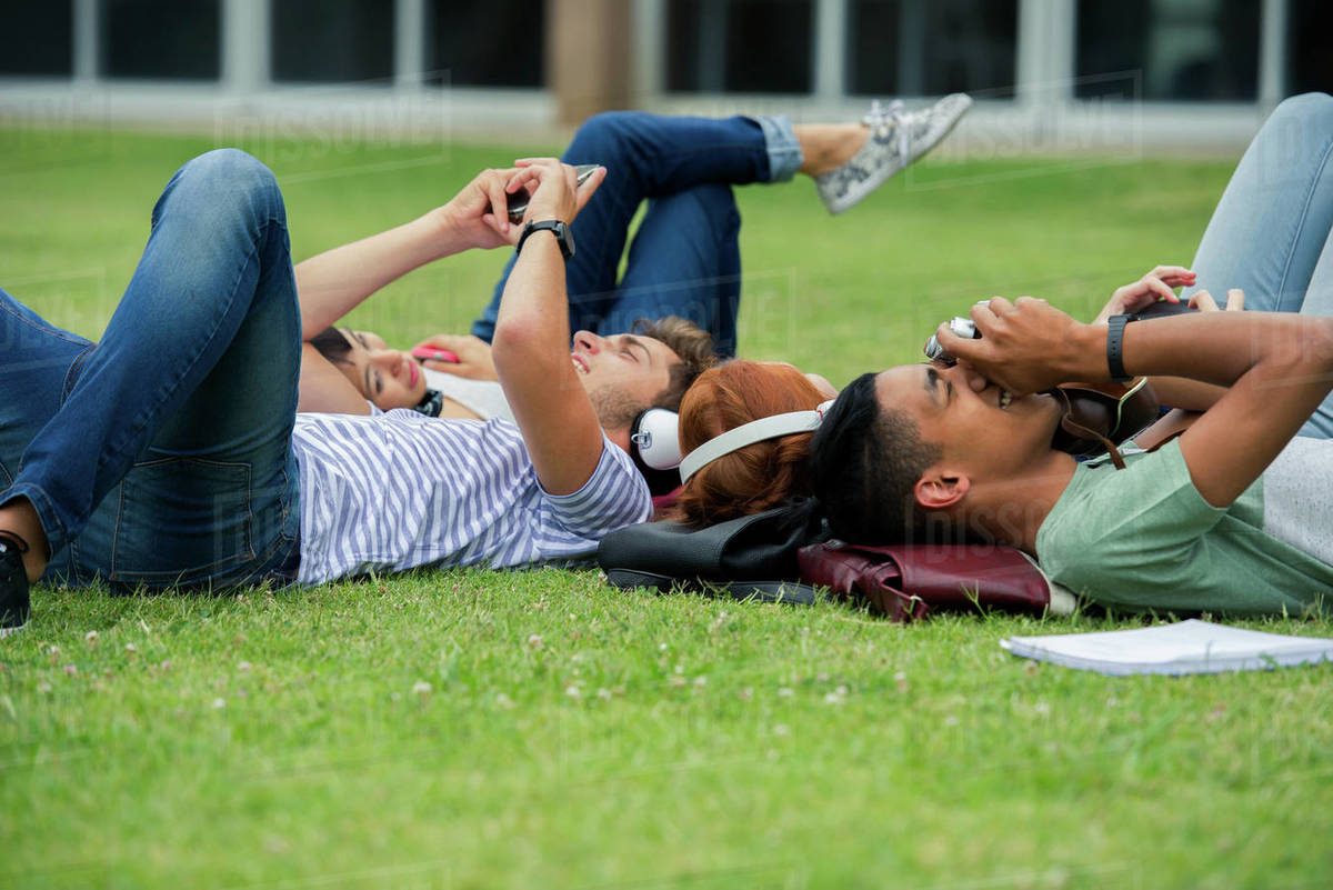 College students relaxing together on lawn between classes - Stock ...