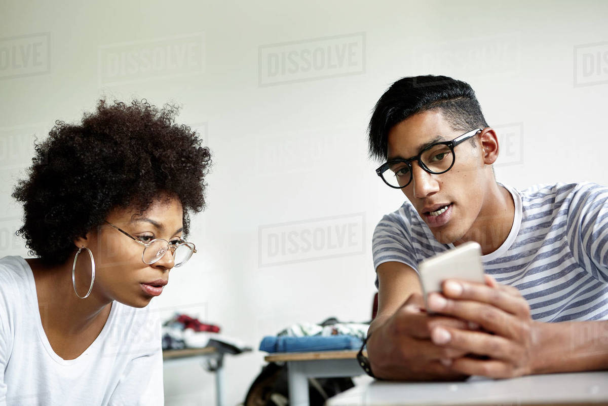 Student showing classmate smart phone - Royalty-free Stock Photo | Dissolve