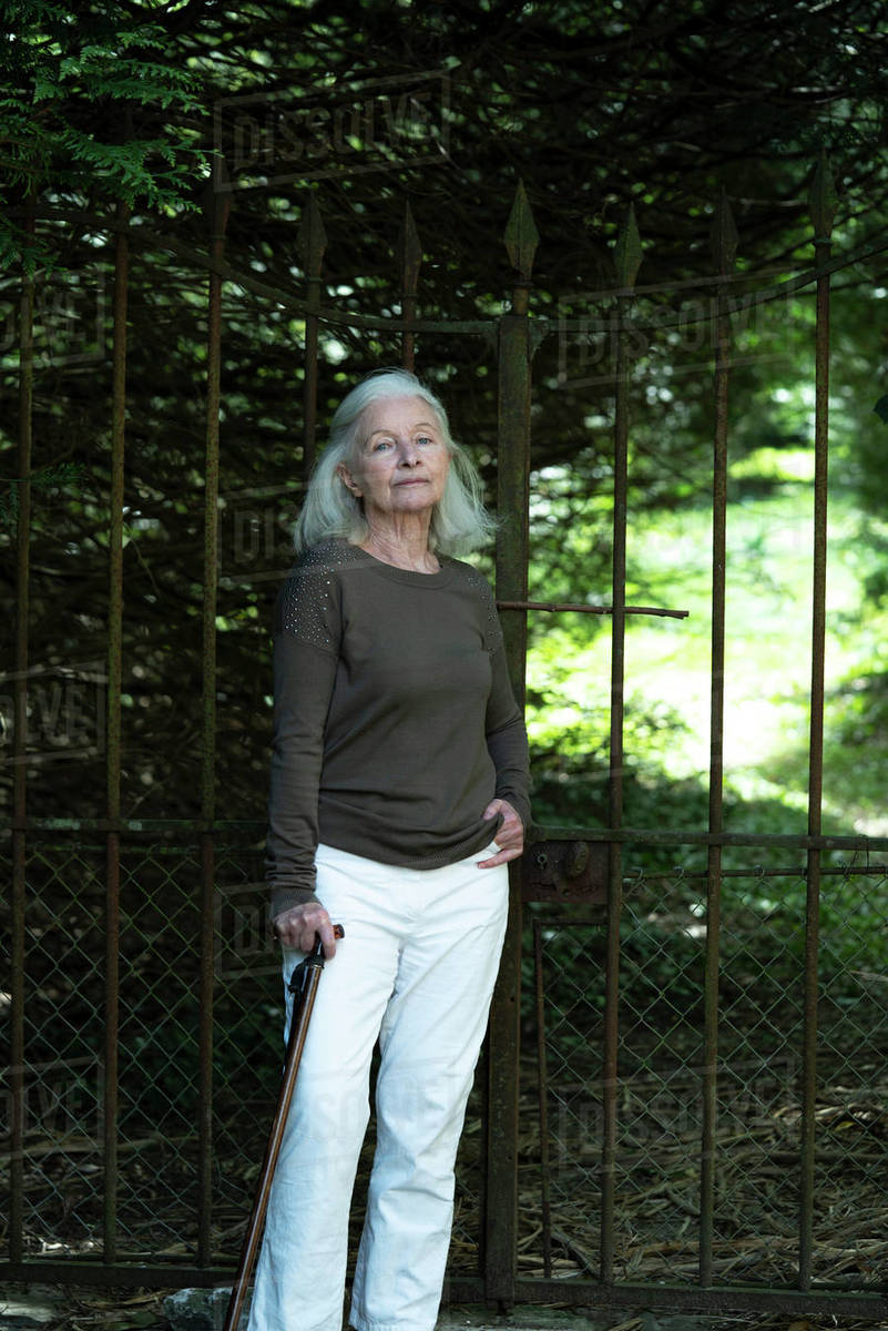 Senior woman standing with walking stick - Royalty-free Stock Photo ...