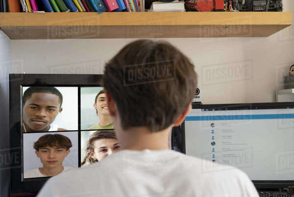 Teenage boy video chatting on the computer with friends at home ...
