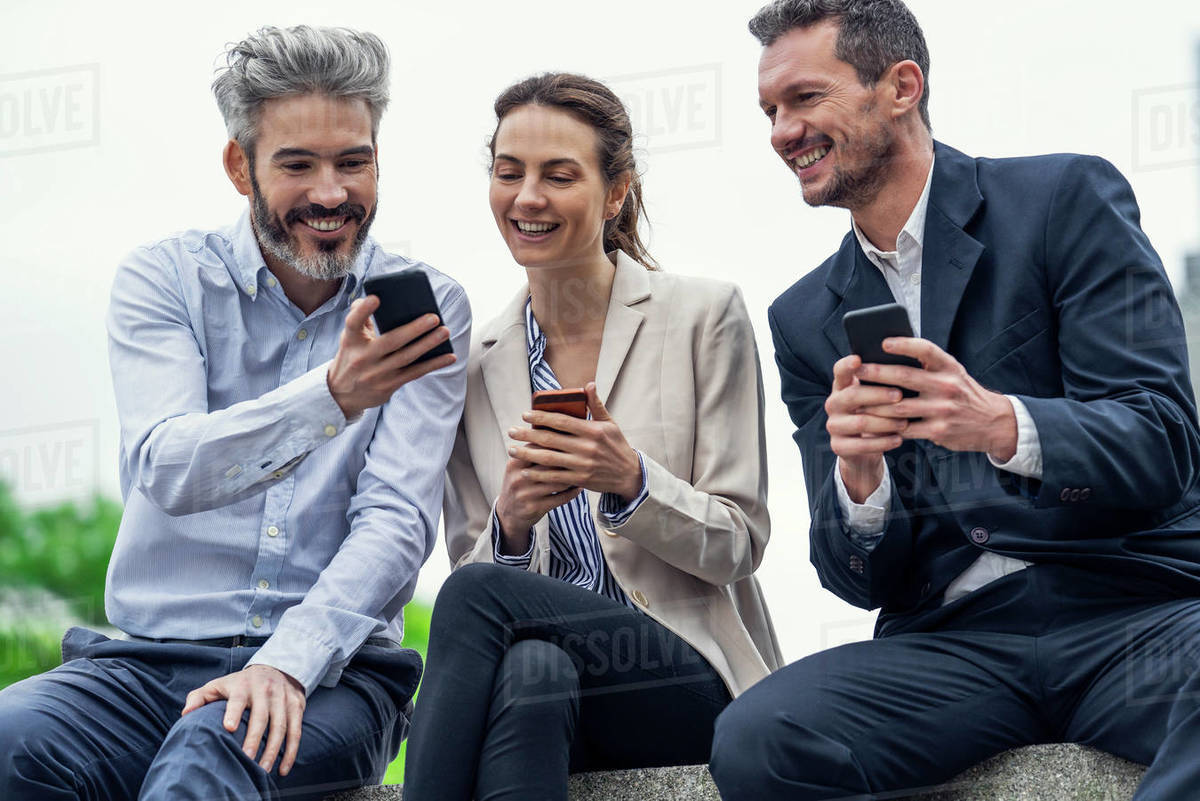 Business people using smartphones in public park - Royalty-free Stock ...