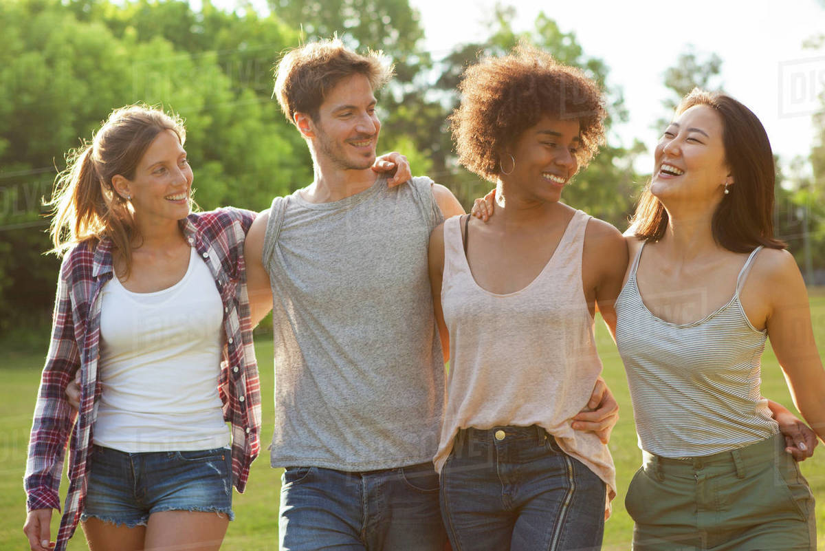 Happy young friends walking together in park - Stock Photo - Dissolve